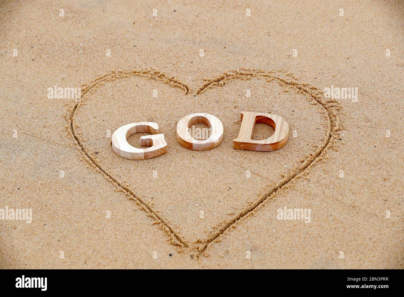 Wooden letters forming the word GOD with heart on a background of beach ...