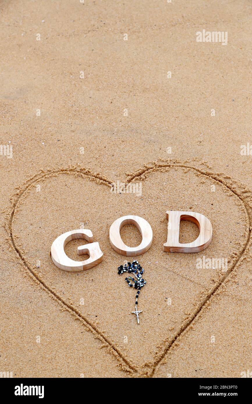 Wooden letters forming the word GOD with heart on a background of beach ...