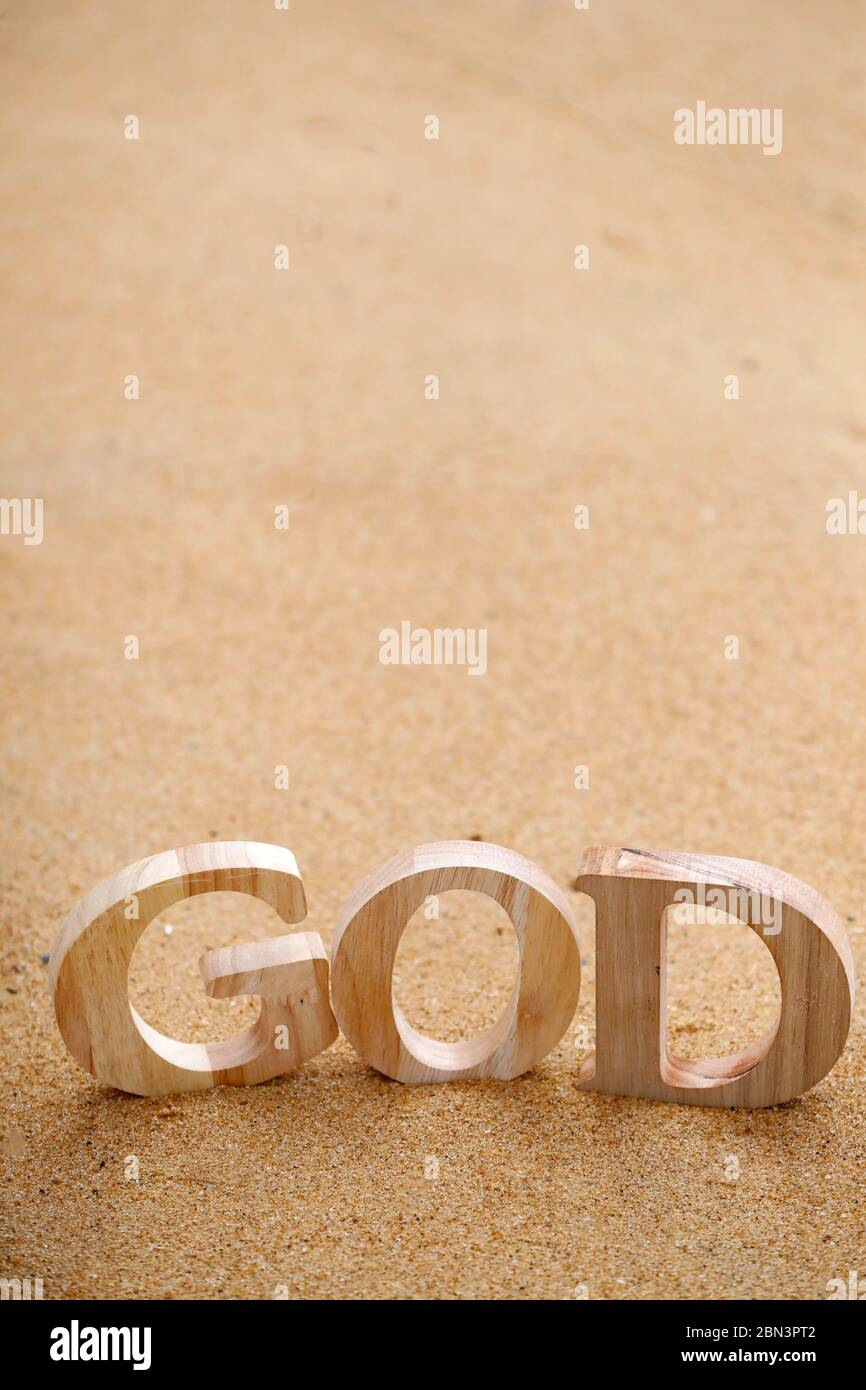 Wooden letters forming the word GOD on a background of beach sand ...