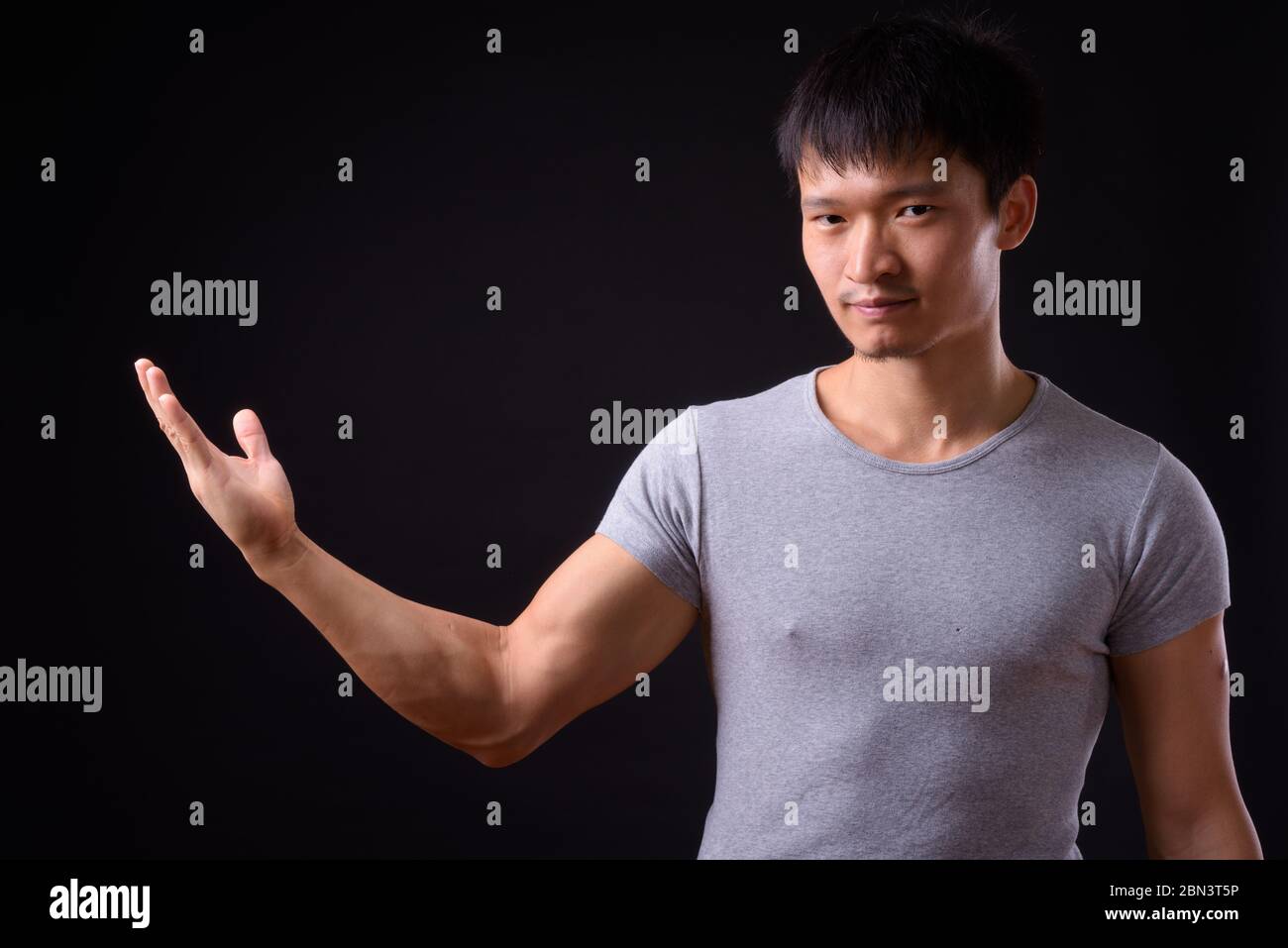 Portrait of young Asian man showing something Stock Photo - Alamy