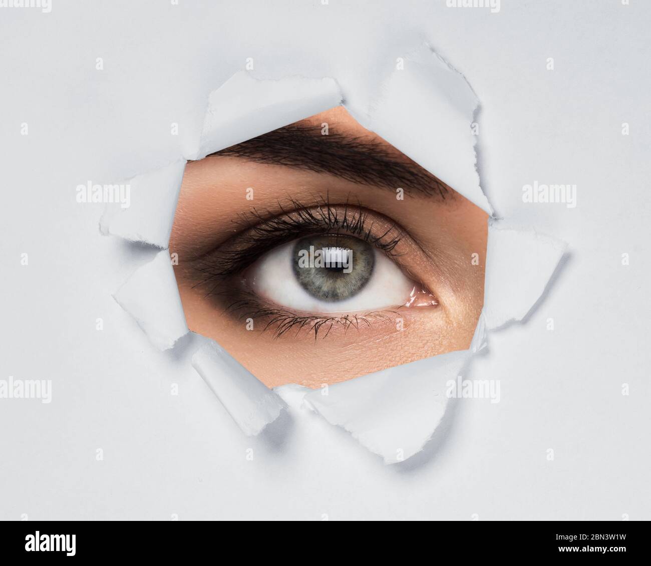 Female eye looking through torn paper Stock Photo - Alamy