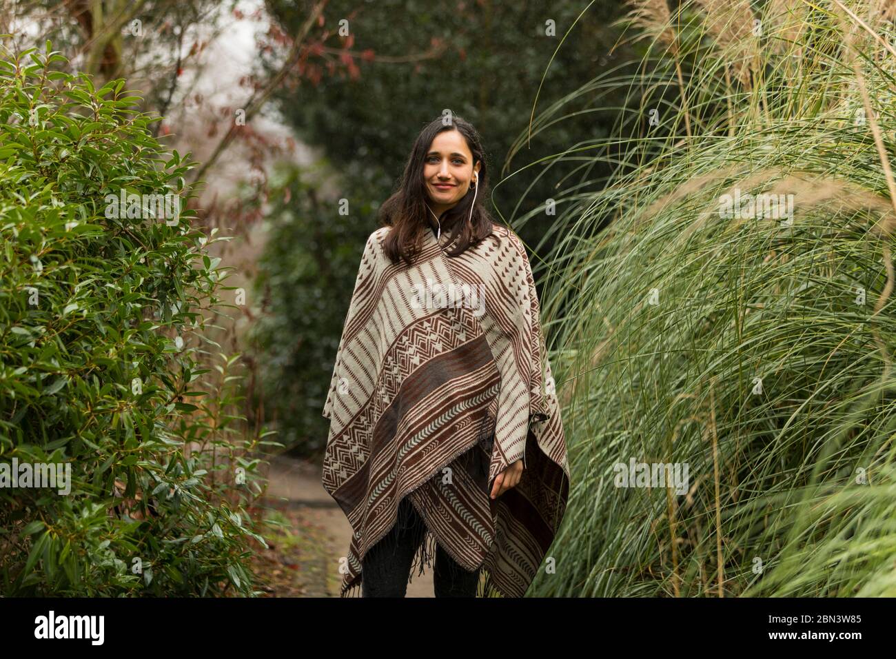 Young woman wearing poncho posing between tall grass in autumn Stock ...