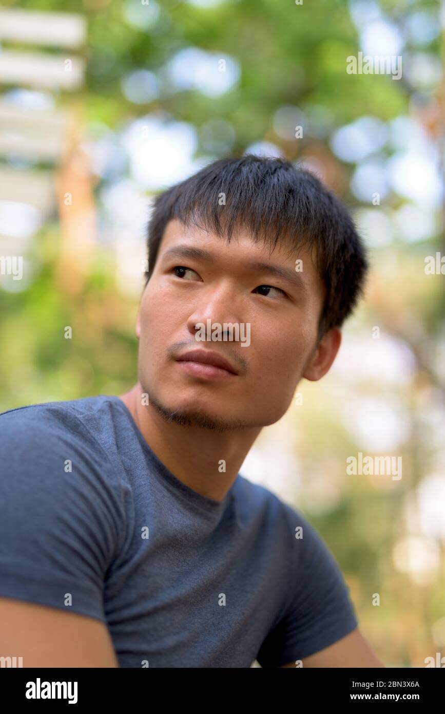 Portrait of young Asian man thinking at the park outdoors Stock Photo ...