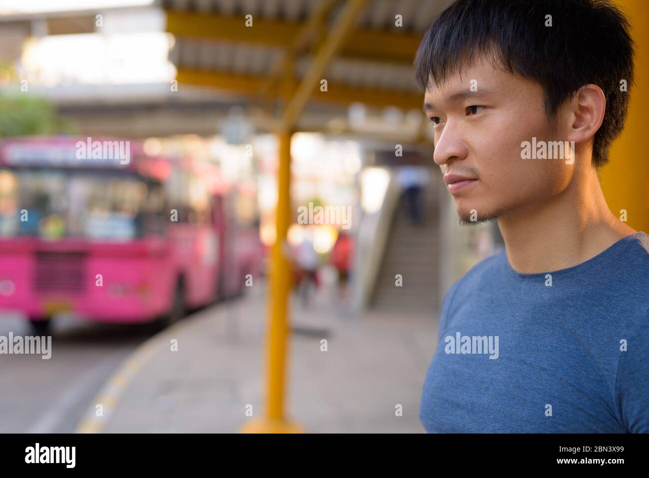 Portrait of young Asian man at the bus stop Stock Photo - Alamy