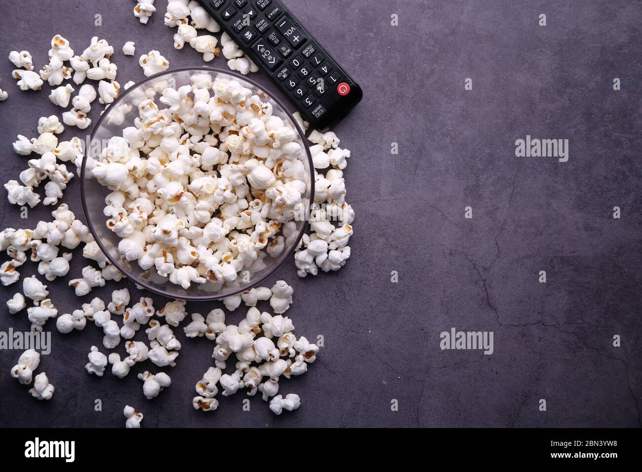 Top view of a bowl of popcorn and tv remote on black background Stock ...