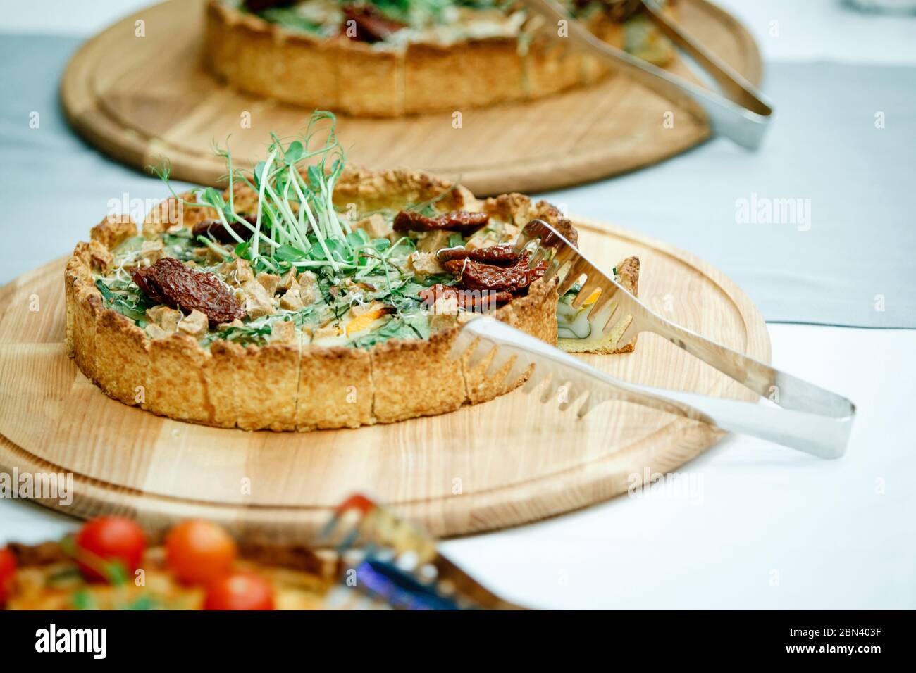 Pies with sprouts on top, chopped into pieces on a banquet table and ...
