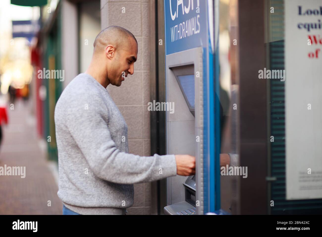 a young man withdrawing cash from a cash point Stock Photo - Alamy
