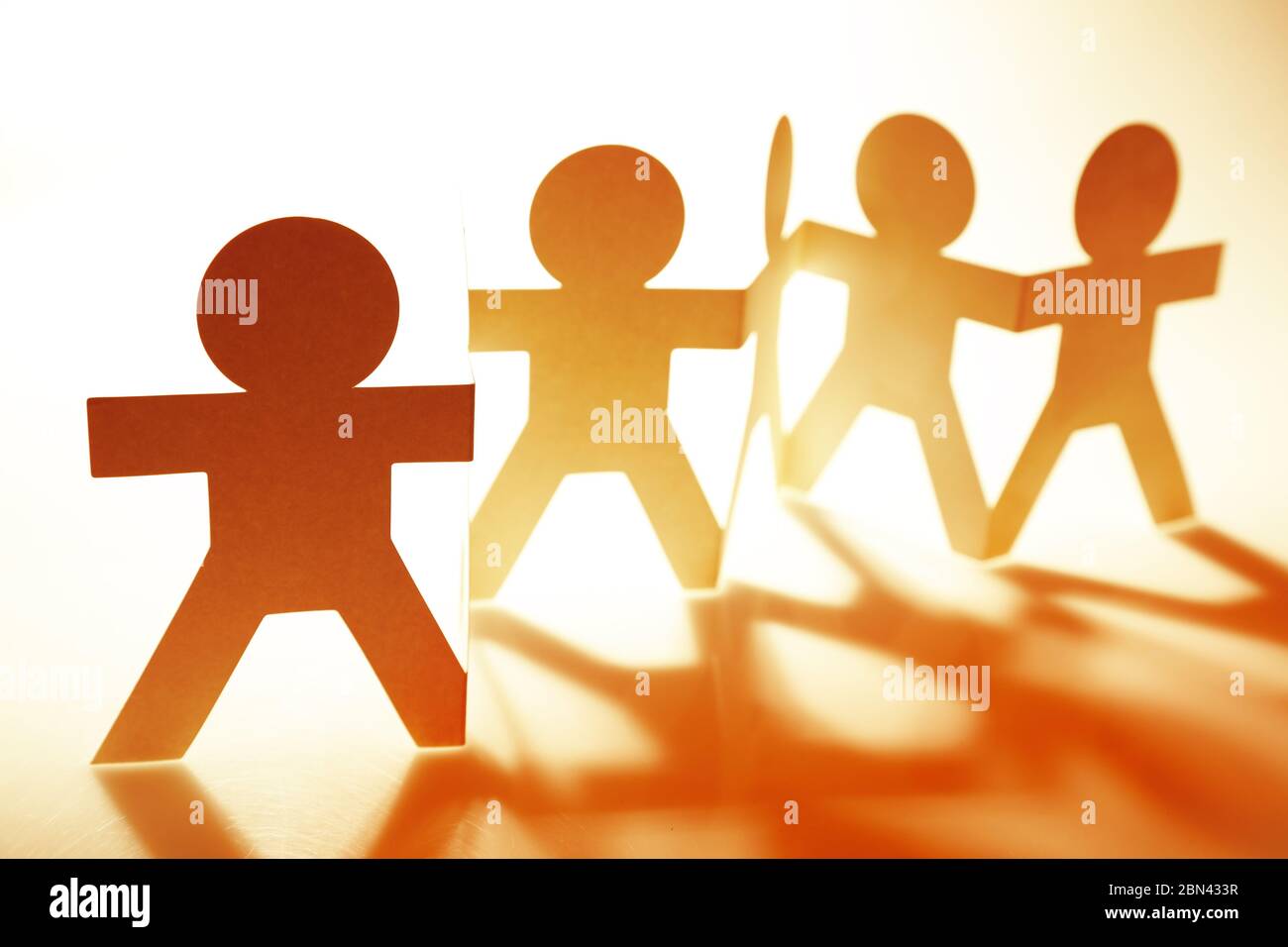 Paper chain team holding hands. Teamwork. Partnership Stock Photo - Alamy