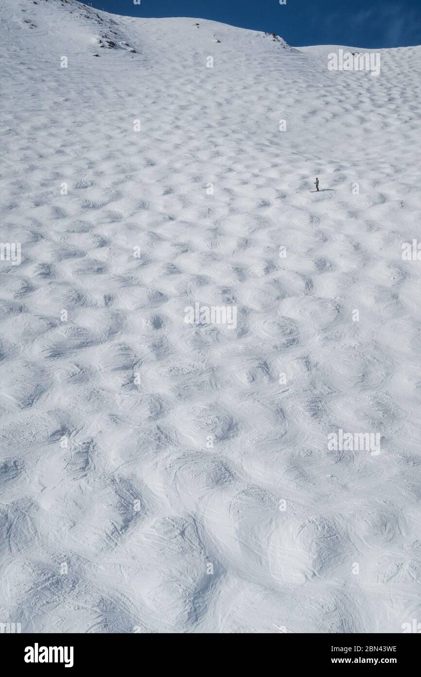 High views of a mogul run at a ski resort in the winter. A lone skier ...