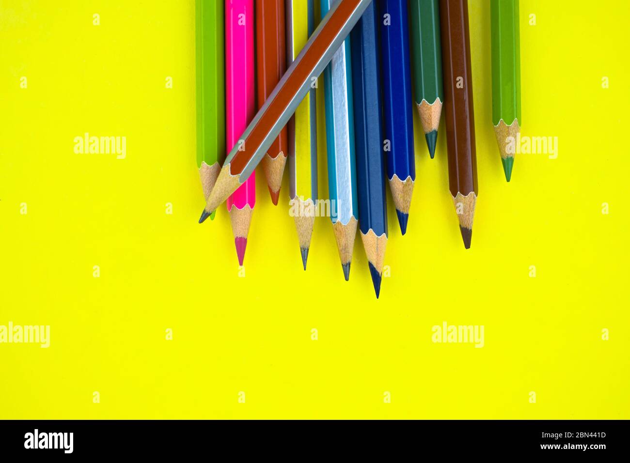 Heap of different colored wood pencil crayons placed on top of a yellow ...