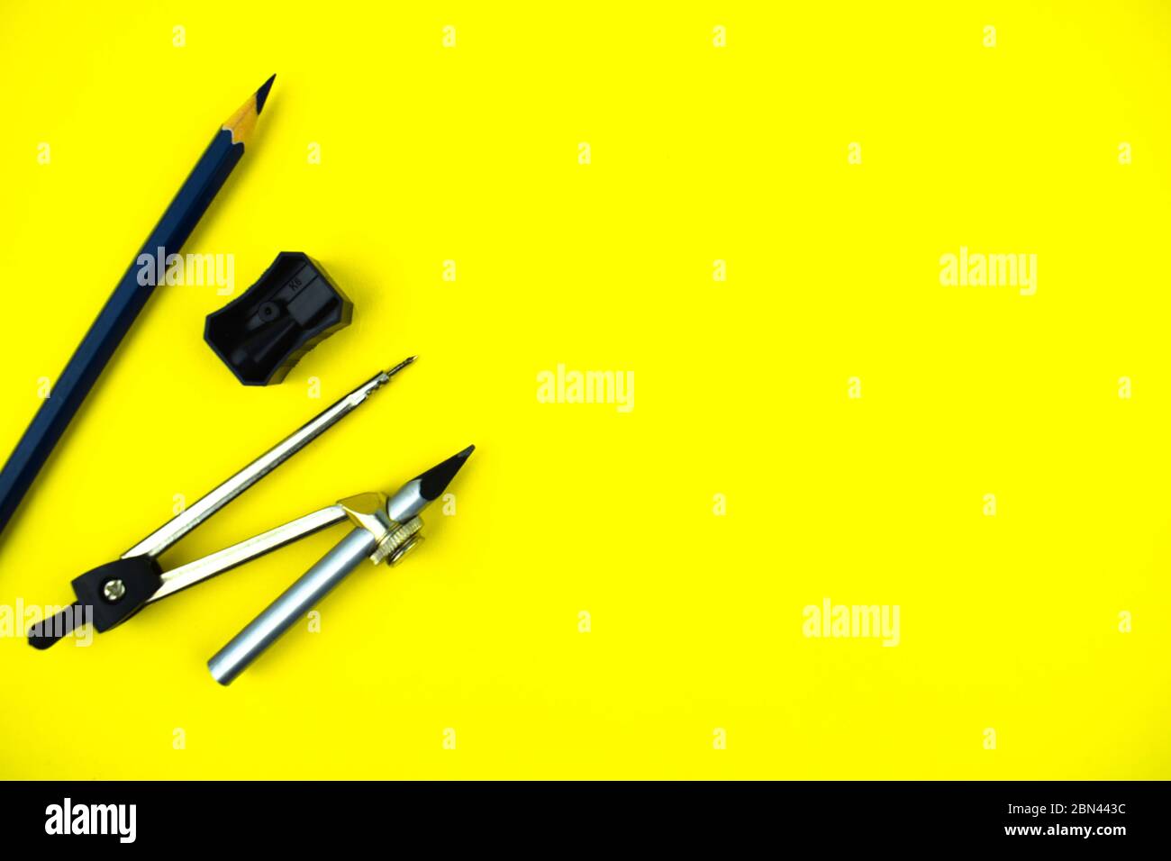 One black pencil crayon,a pencil sharpener and a compass attached to a ...