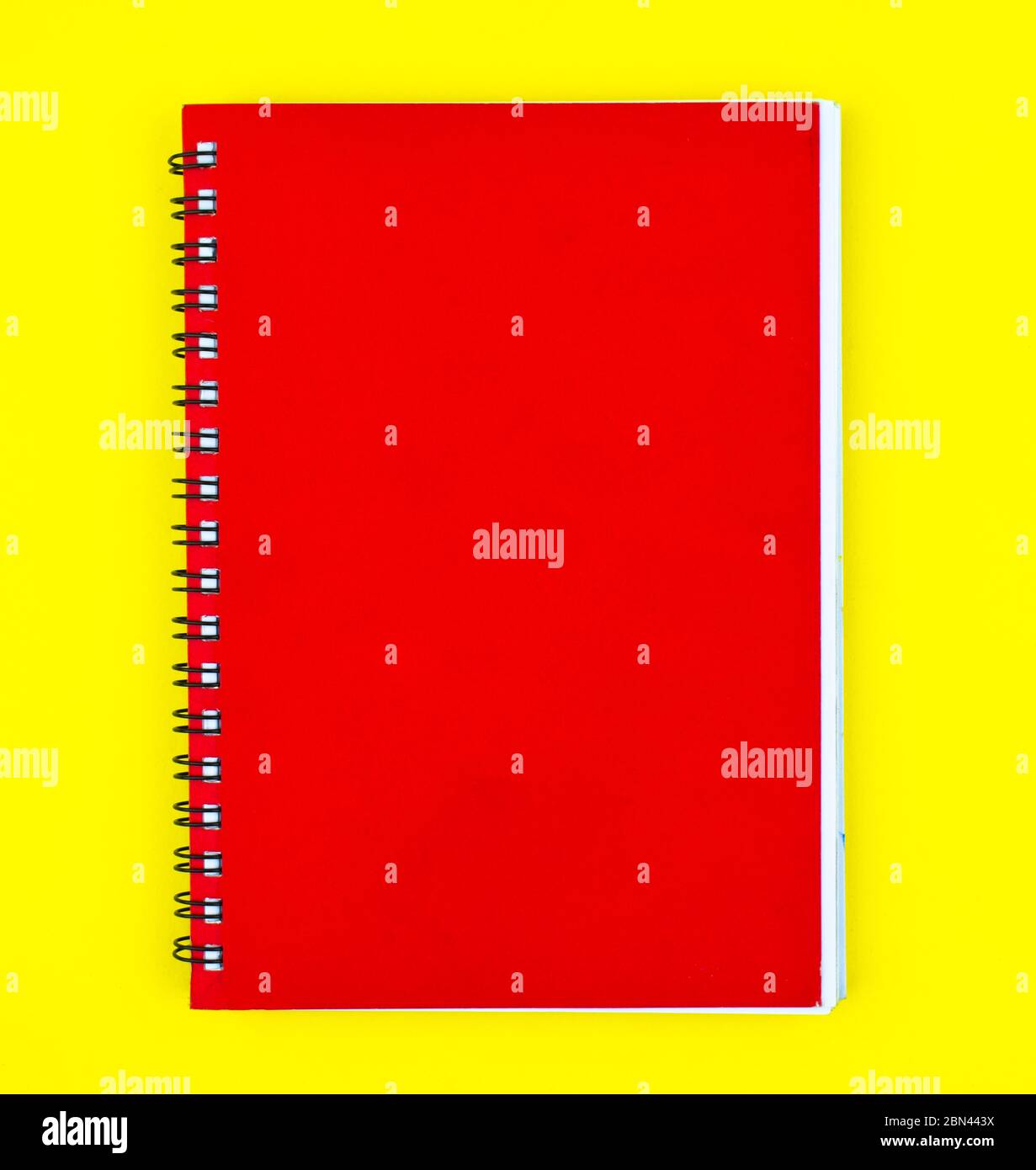 One red colored note paper diary placed on a isolated yellow paper ...