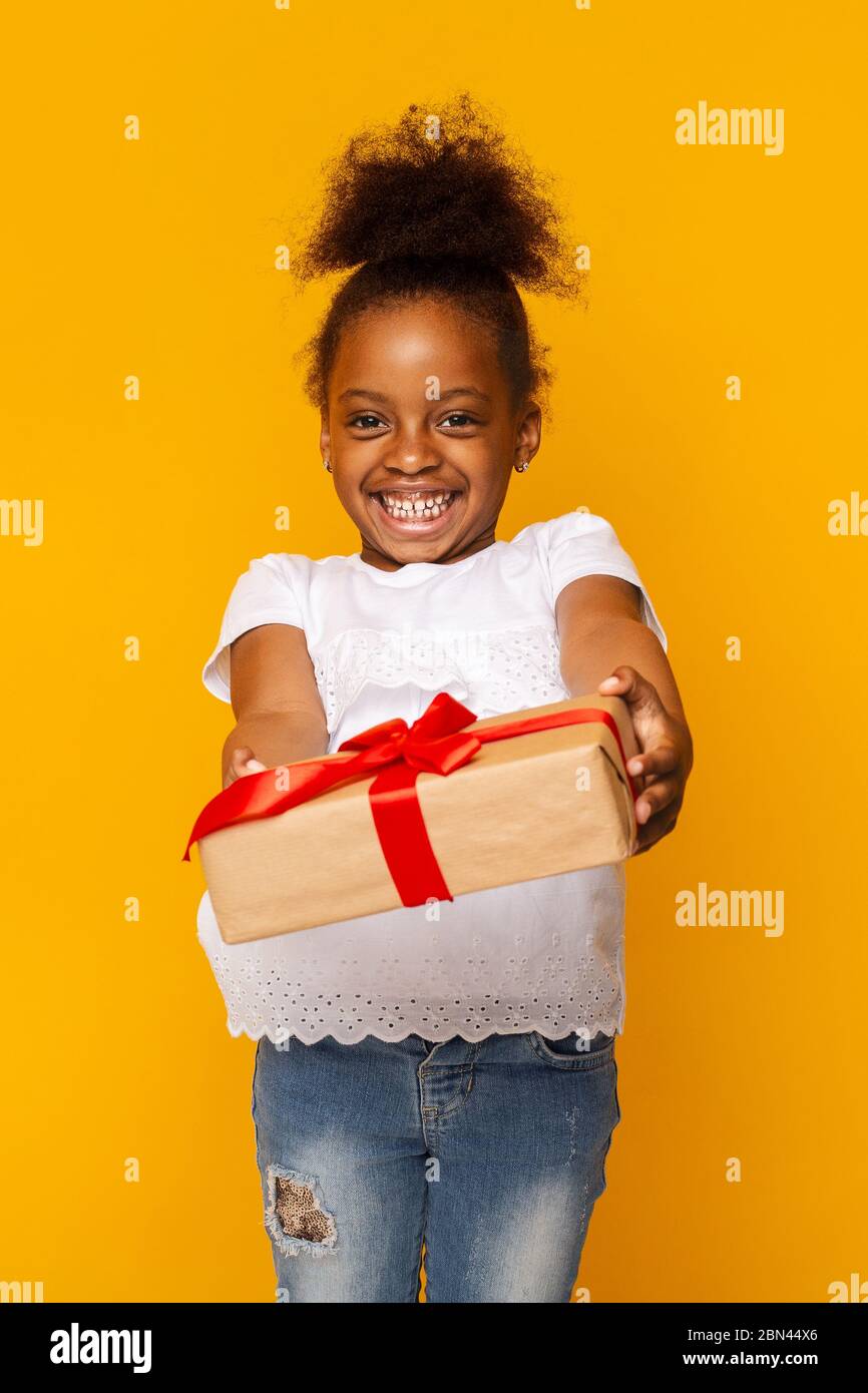 Cute shy little african girl giving gift box at camera Stock Photo - Alamy