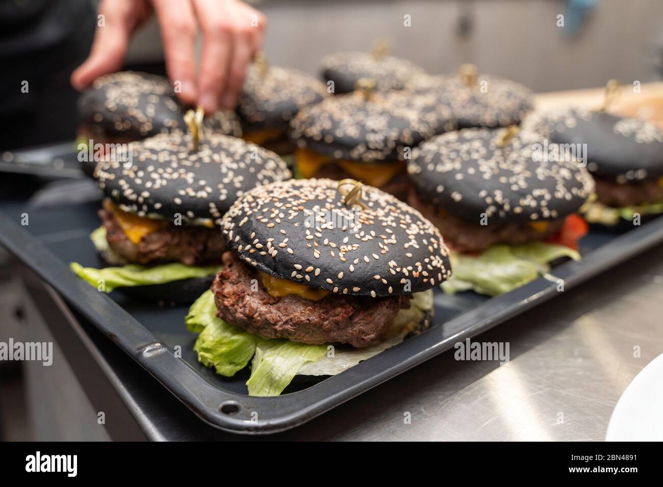 Chef cooking a batch of black burgers Stock Photo - Alamy