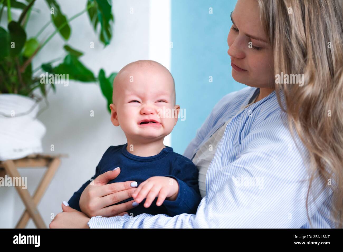 Mom hugs crying moody kid tantrum. Little baby child on mother hands ...
