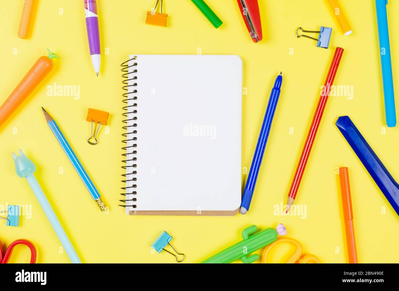 Colored different school supplies on soft yellow paper background ...