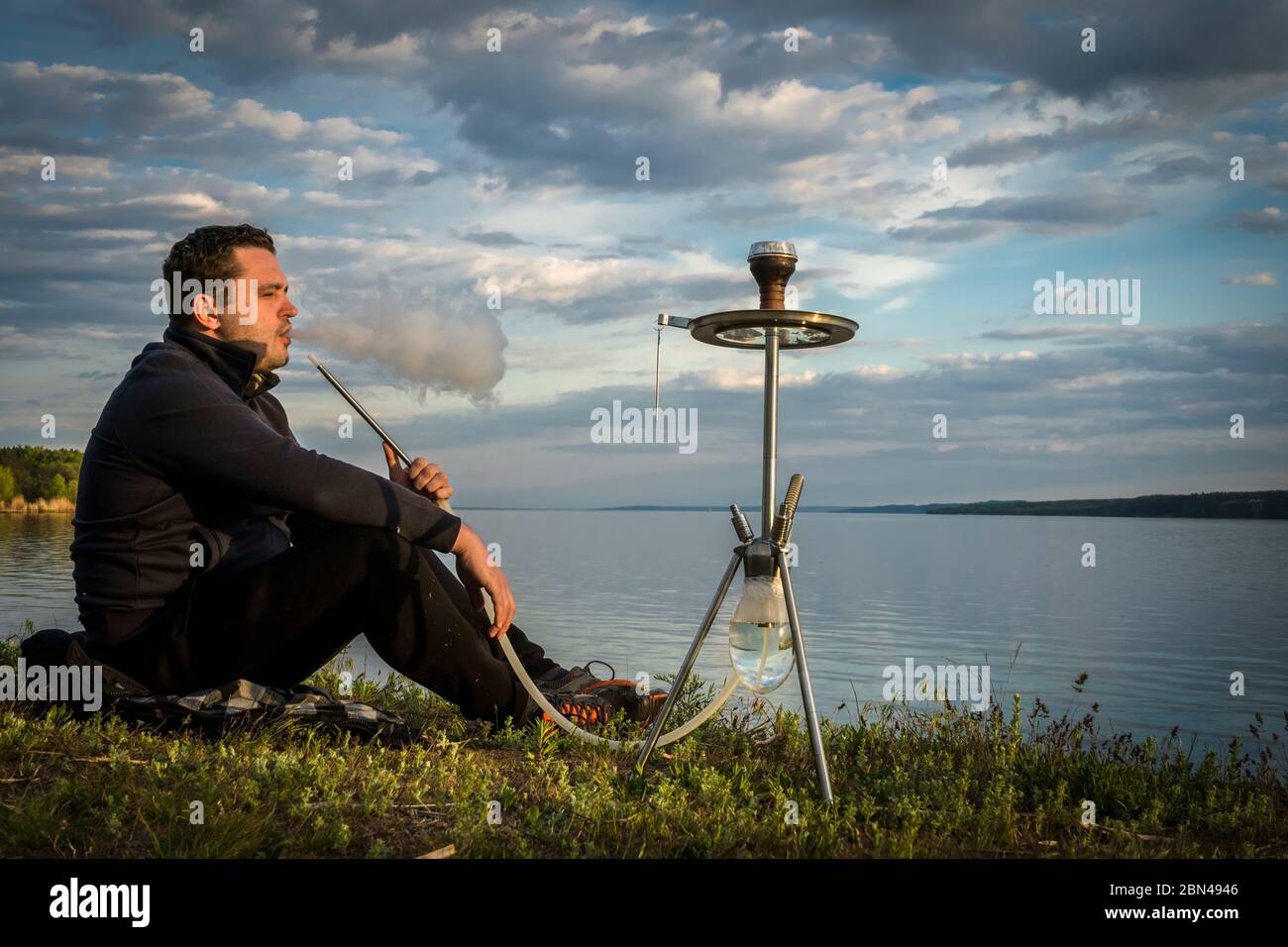 Man smoking hookah outside near the river Stock Photo - Alamy