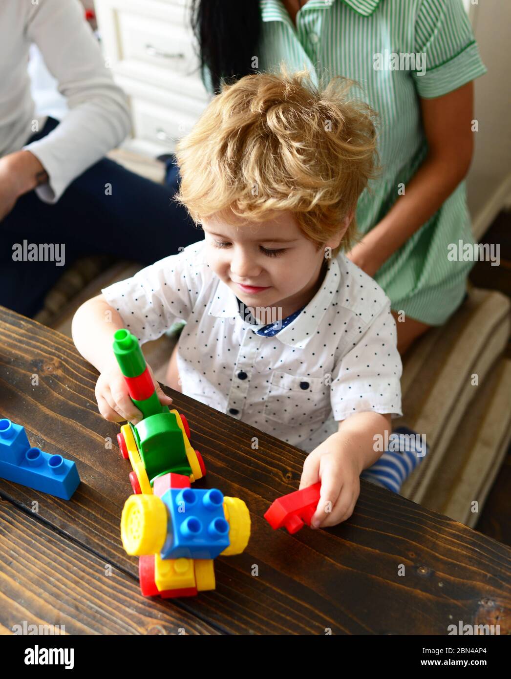 Boy spends fun time in playroom. Parents on background and kid with ...