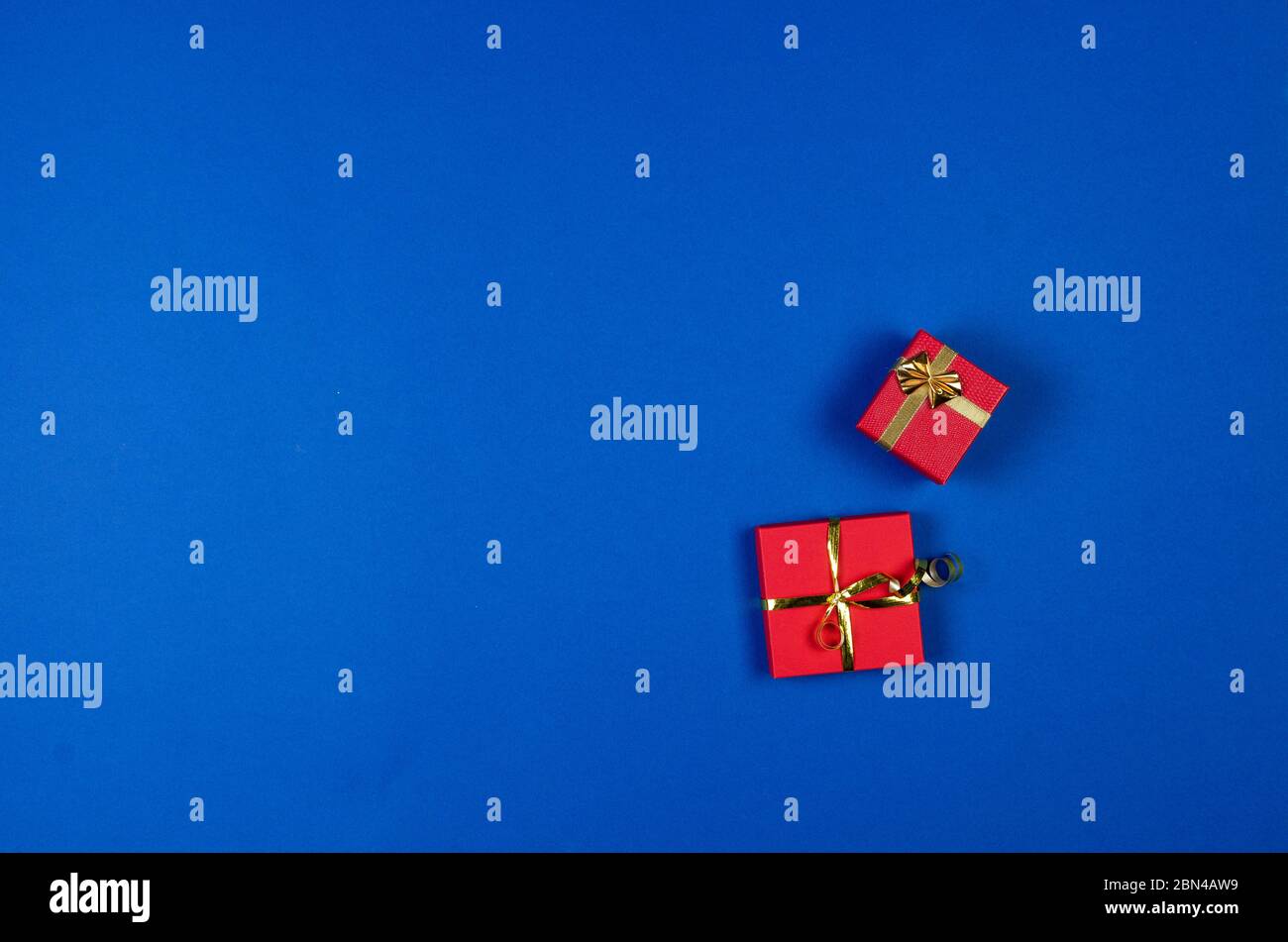 Two red gift boxes with golden ribbon on blue background. Top view ...