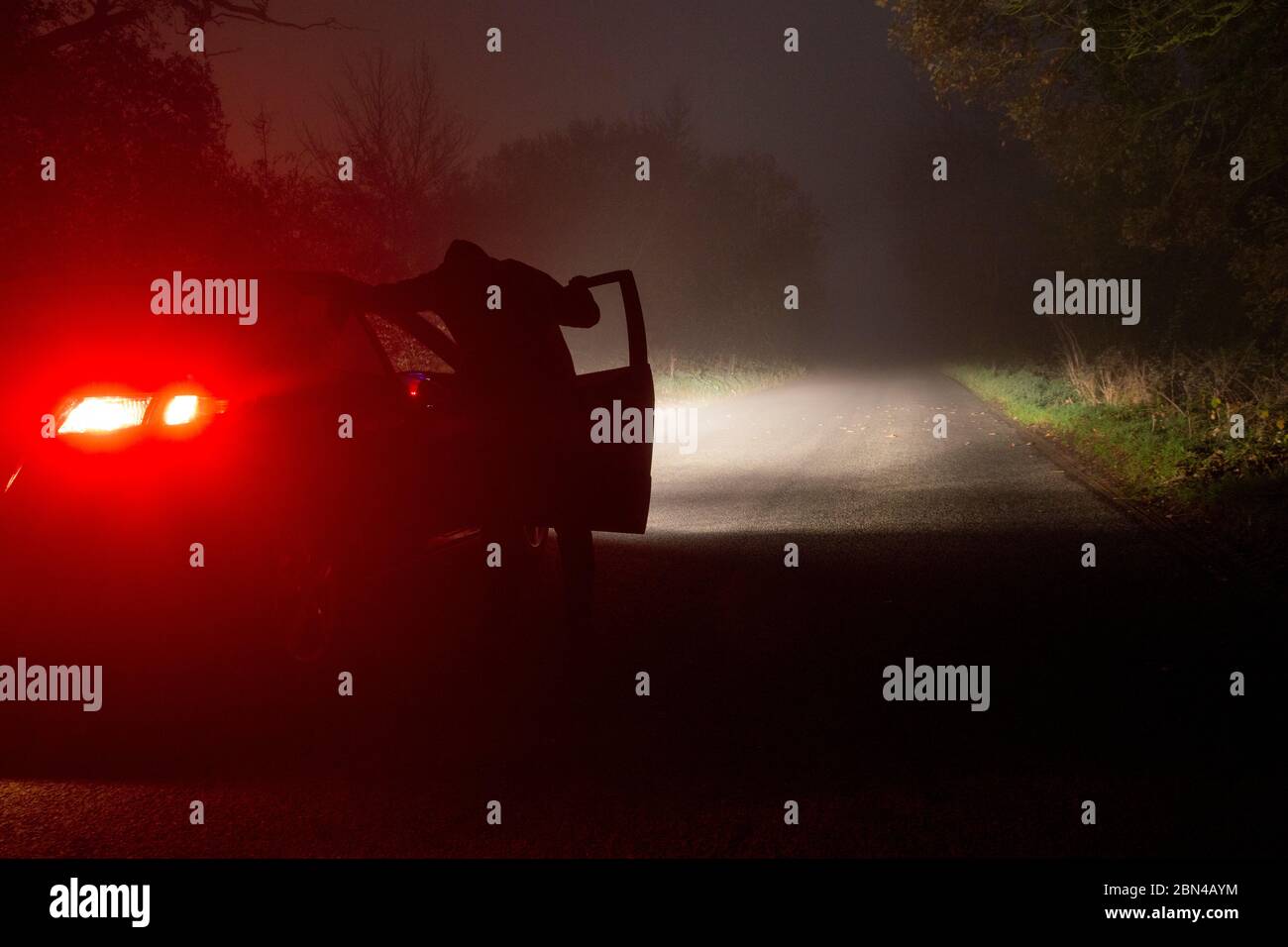 A spooky, mysterious hooded figure, looking into a car with the door ...