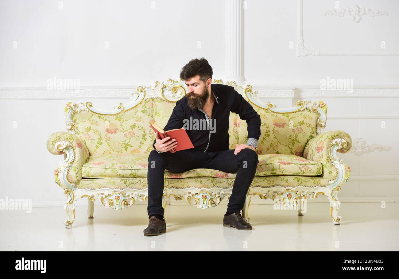 Lecturer sit on sofa and reading book, white wall background. Scientist ...