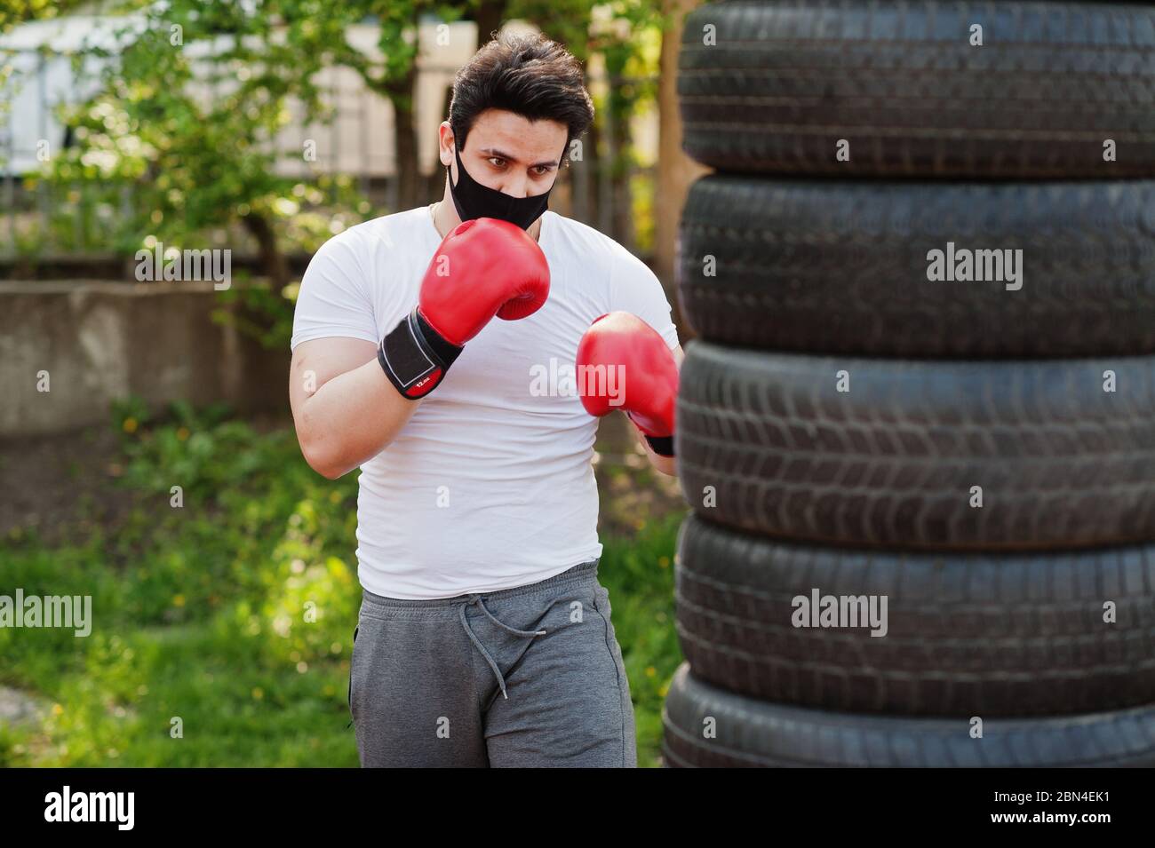 Portrait sports arabian boxer man in black medical face mask boxing ...