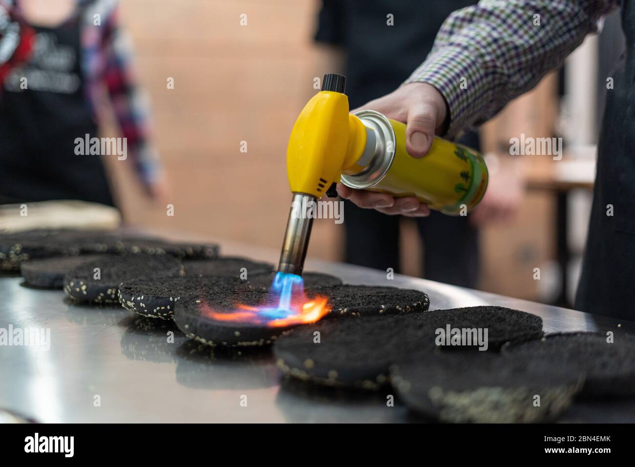 Cook using a kitchen torch to crisp up buns Stock Photo - Alamy