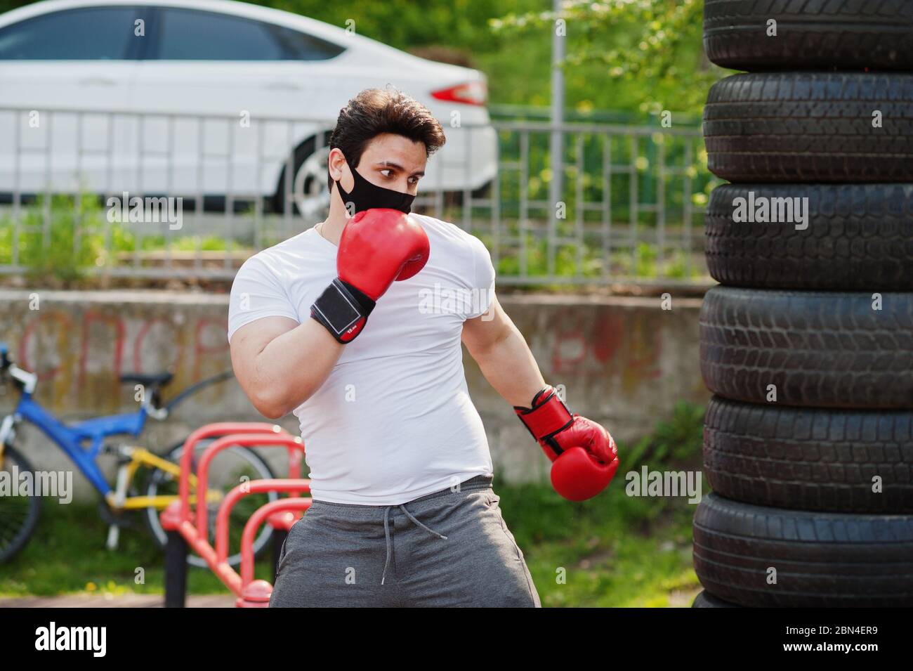 Portrait sports arabian boxer man in black medical face mask boxing ...