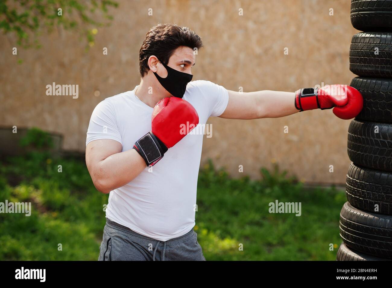 Portrait sports arabian boxer man in black medical face mask boxing ...