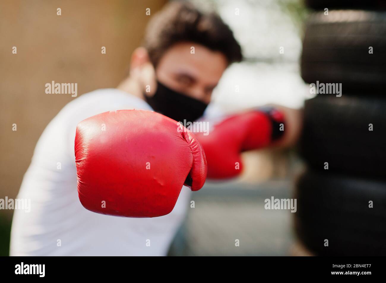 Portrait sports arabian boxer man in black medical face mask boxing ...