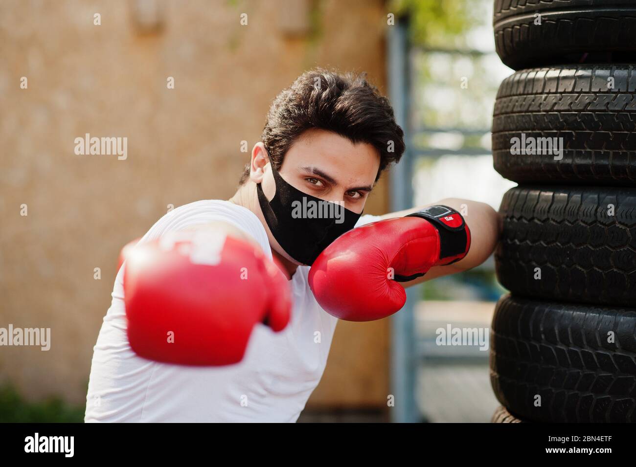 Portrait sports arabian boxer man in black medical face mask boxing ...