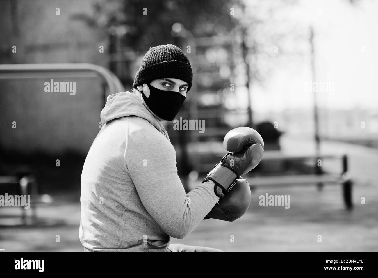 Portrait sports arabian boxer man in black medical face mask boxing ...