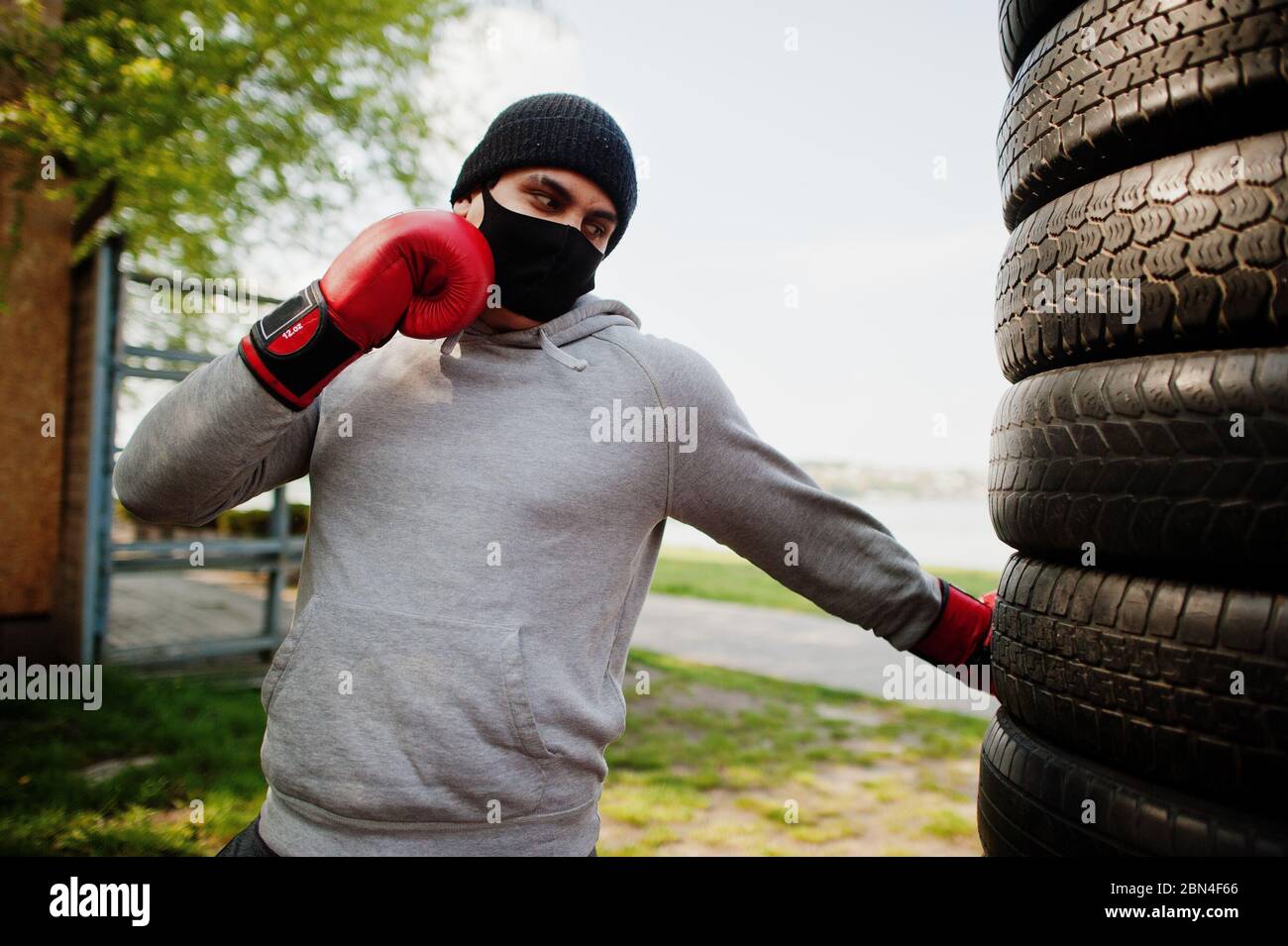 Portrait sports arabian boxer man in black medical face mask boxing ...