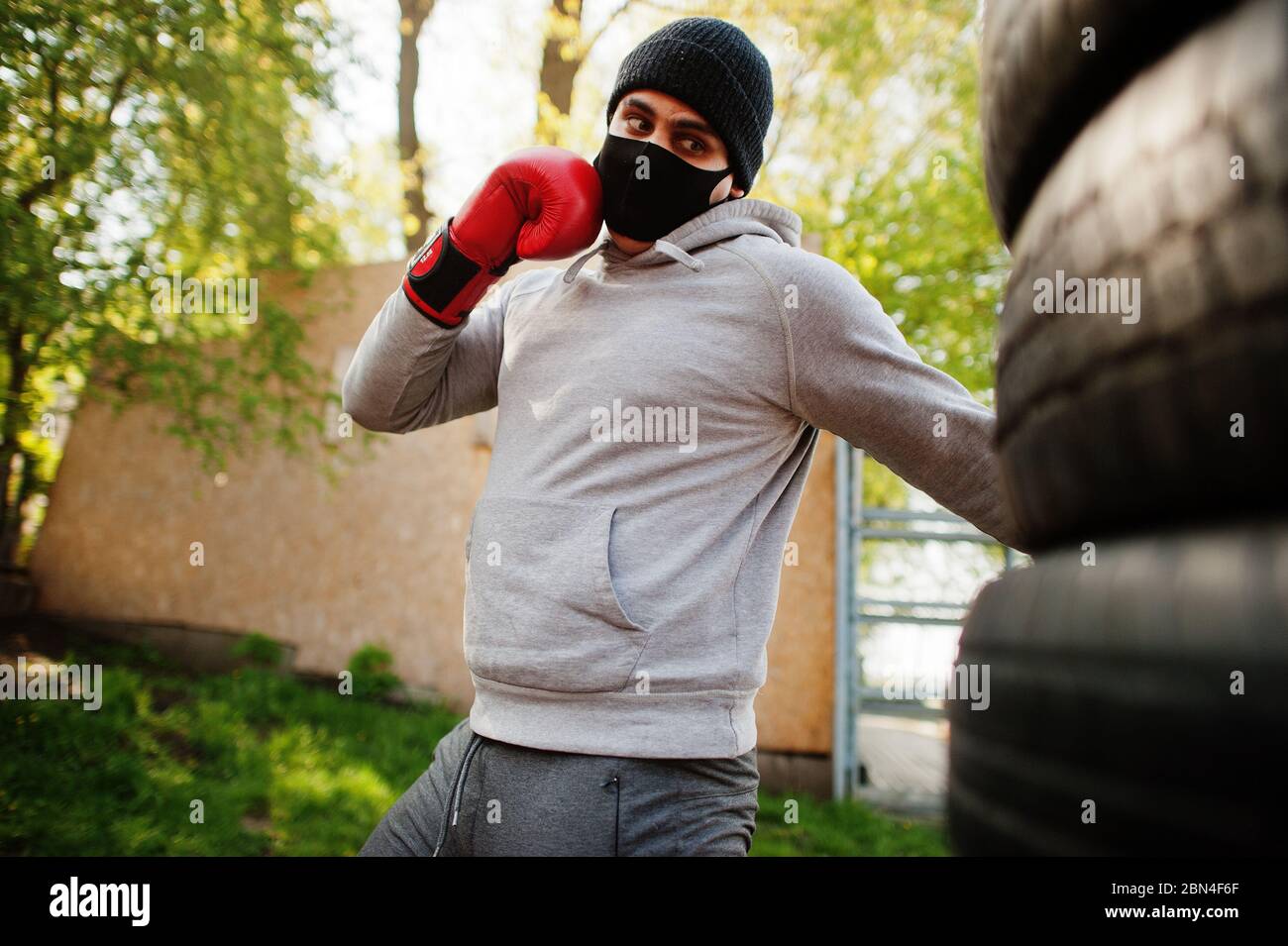 Portrait sports arabian boxer man in black medical face mask boxing ...