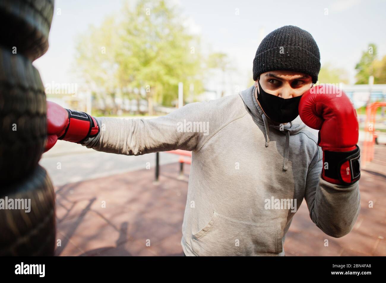Portrait sports arabian boxer man in black medical face mask boxing ...