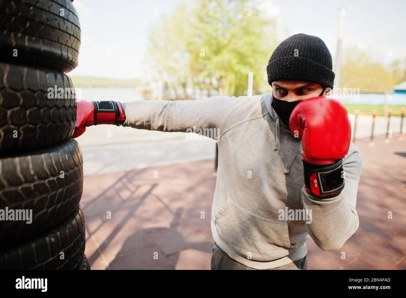 Portrait sports arabian boxer man in black medical face mask boxing ...