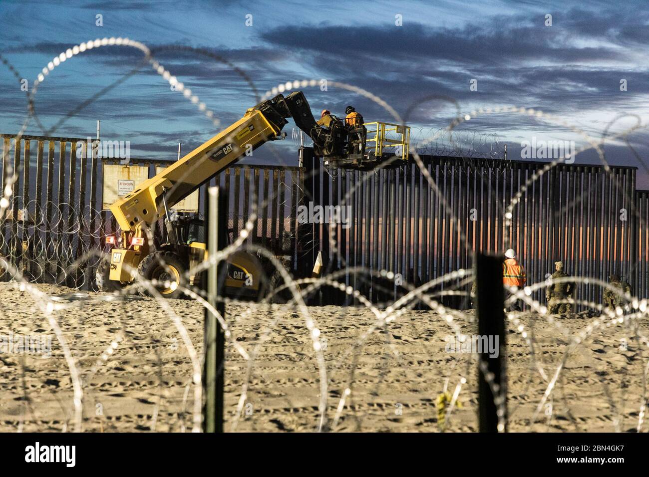U.S. Border Patrol agents monitor personnel reinforcing the border wall ...