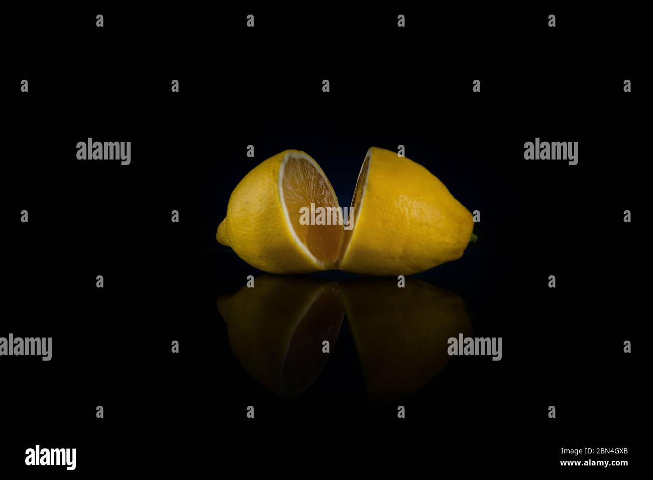 two halves of whole lemon on a black background Stock Photo - Alamy