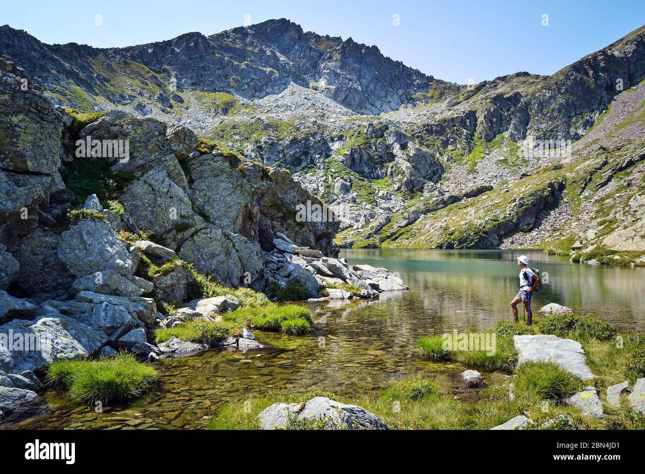 backpacker resting near a mountain lake in a beautiful summer's day ...