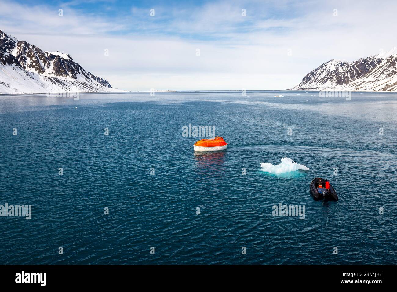 Maneuvering orange lifeboat in water in Arctic waters, Svalbard ...