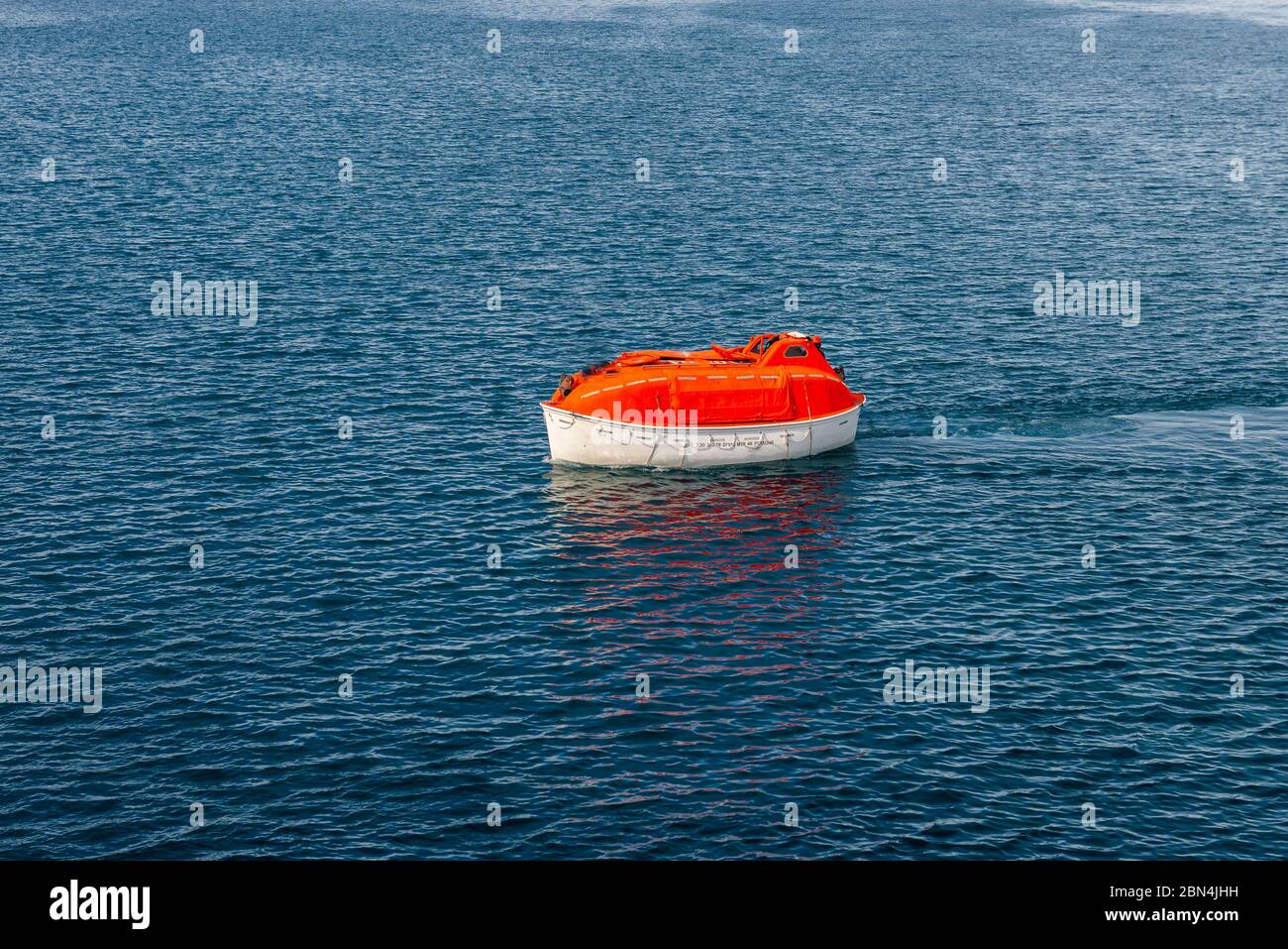 Maneuvering orange lifeboat in water in Arctic waters, Svalbard ...