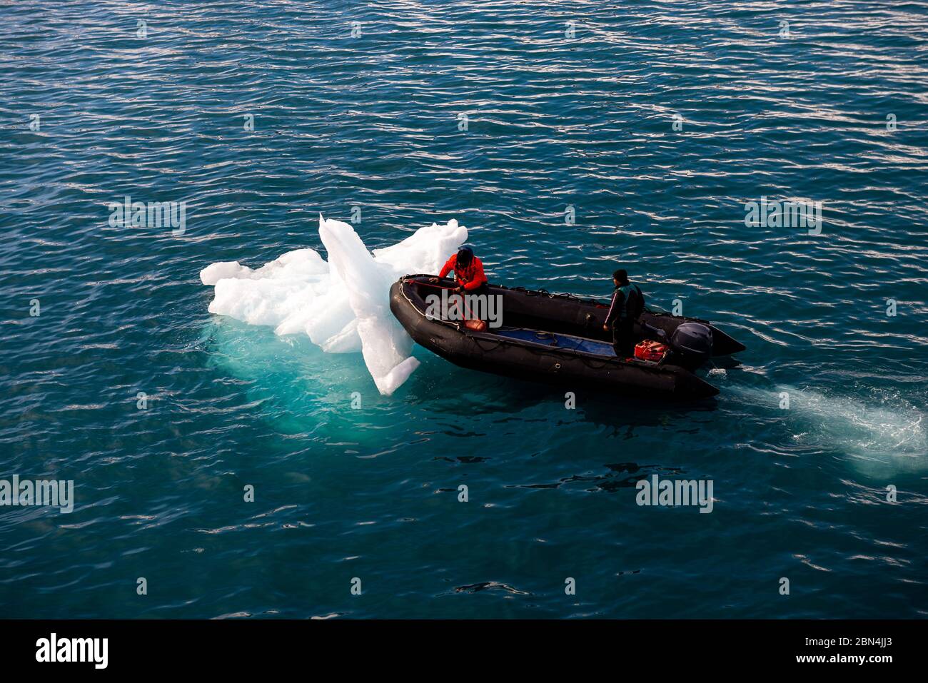 Inflatable boat with one person in Arctic waters, Svalbard. Pushing ice ...