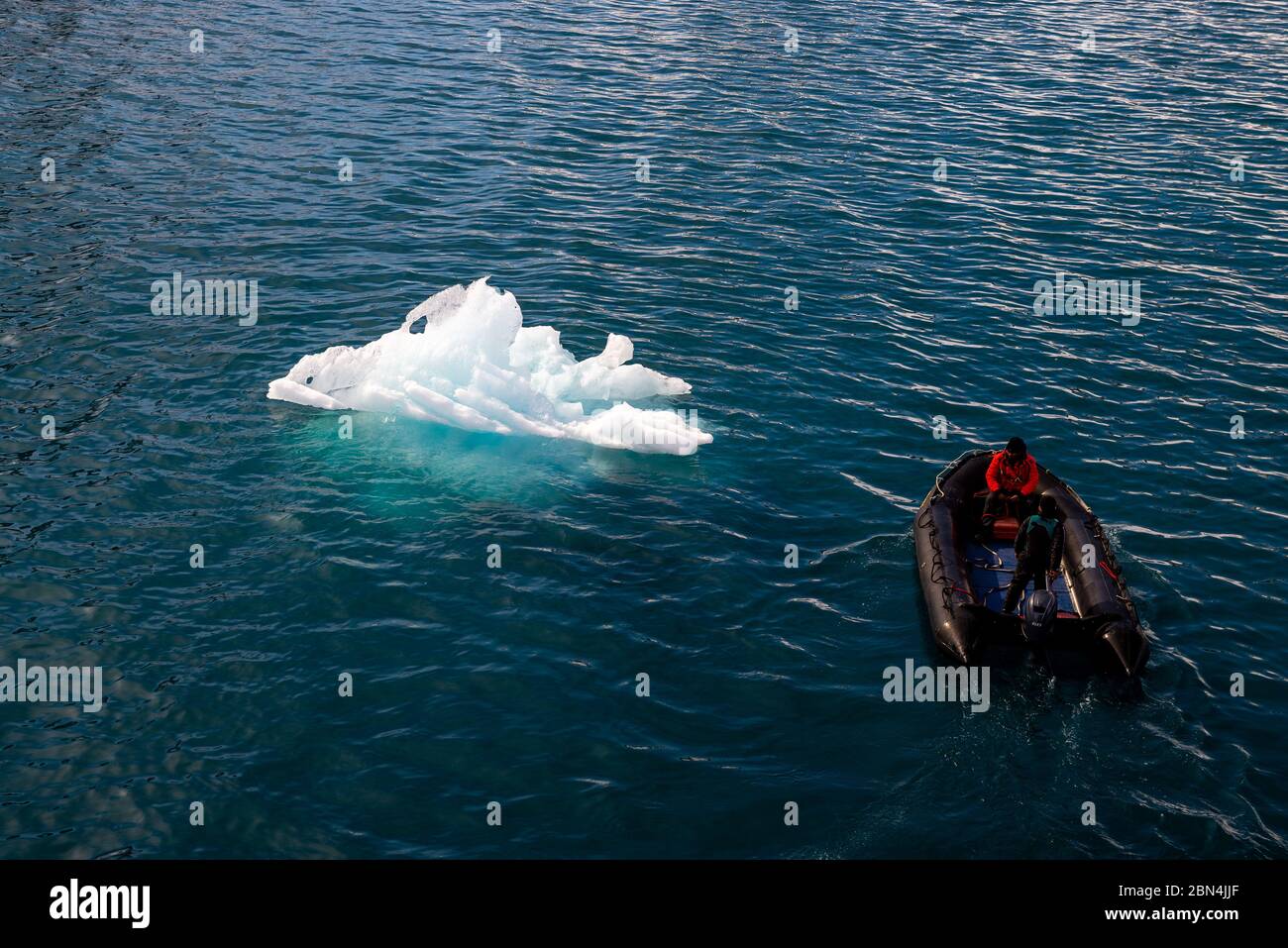 Inflatable boat with one person in Arctic waters, Svalbard. Pushing ice ...