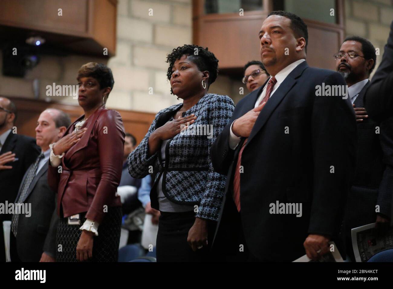 Attendees stand as Erica Spell of USAID sings the National Anthem at ...