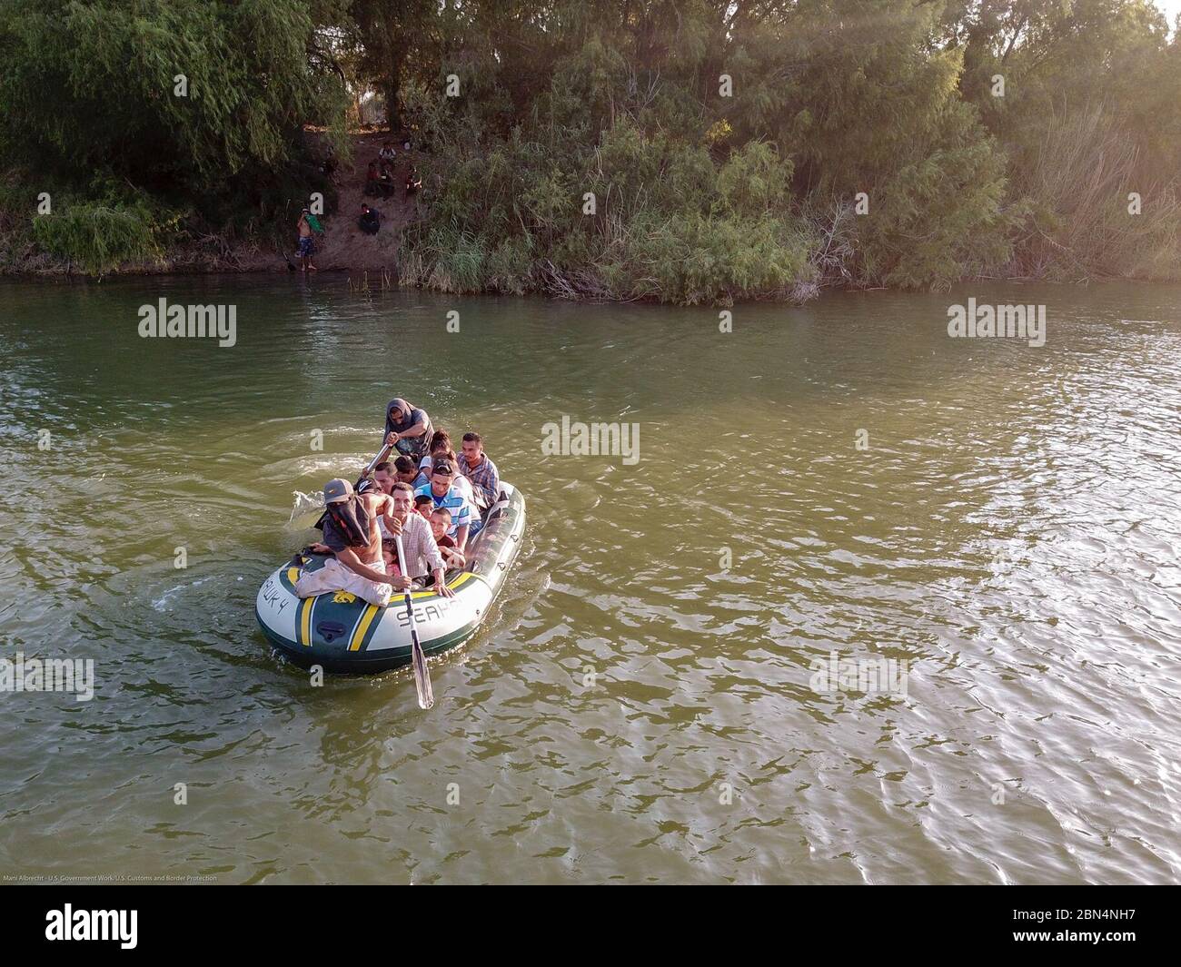 A group of 11 migrants, accompanied by two smugglers, crosses the Rio ...