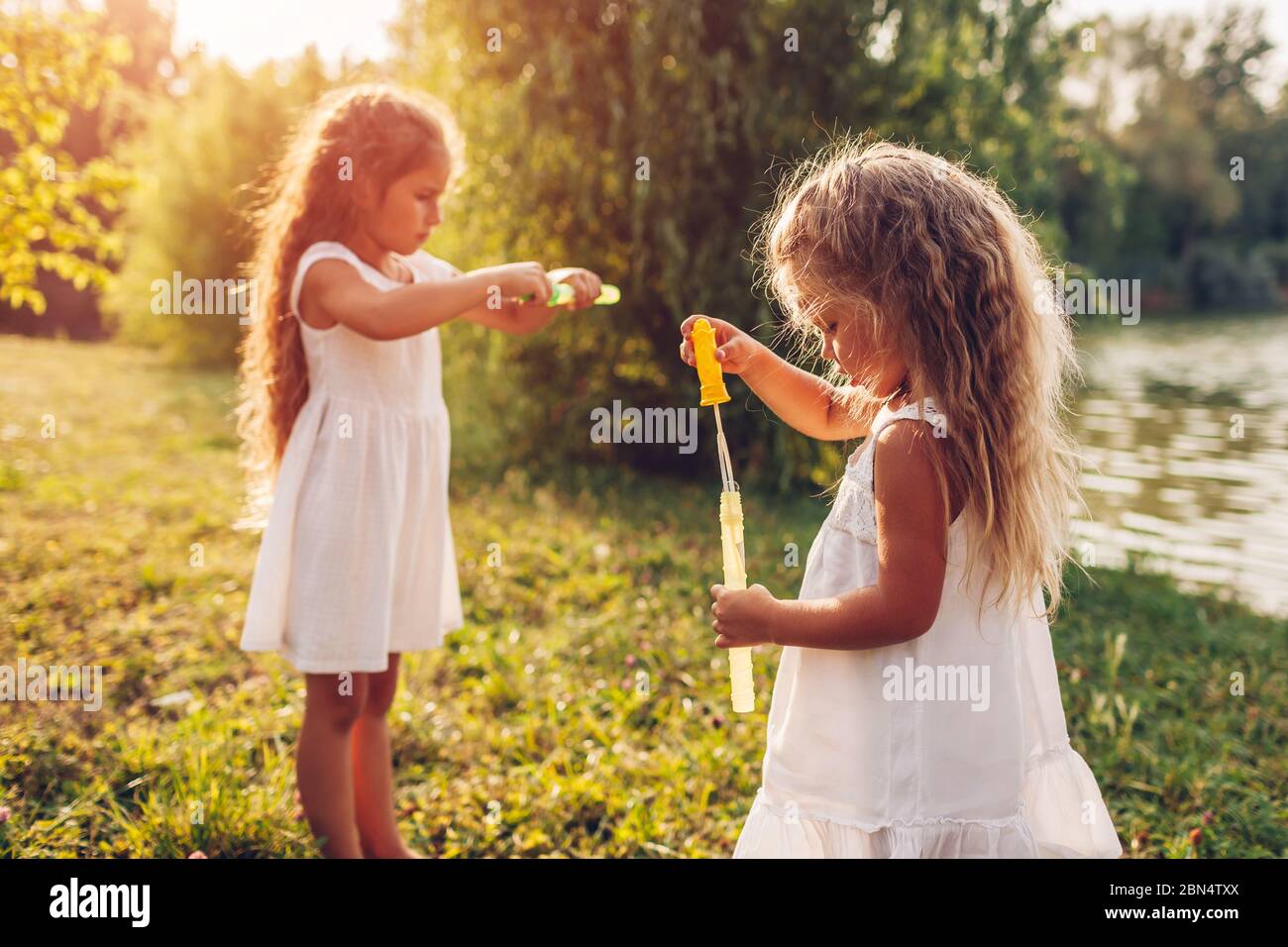 Little girls sisters blowing bubbles in spring park. Kids having fun ...