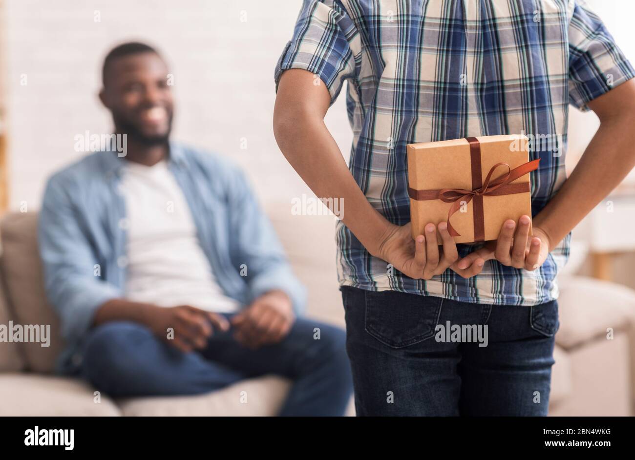 Boy greeting dad with Fathers Day, hiding present behind his back Stock ...