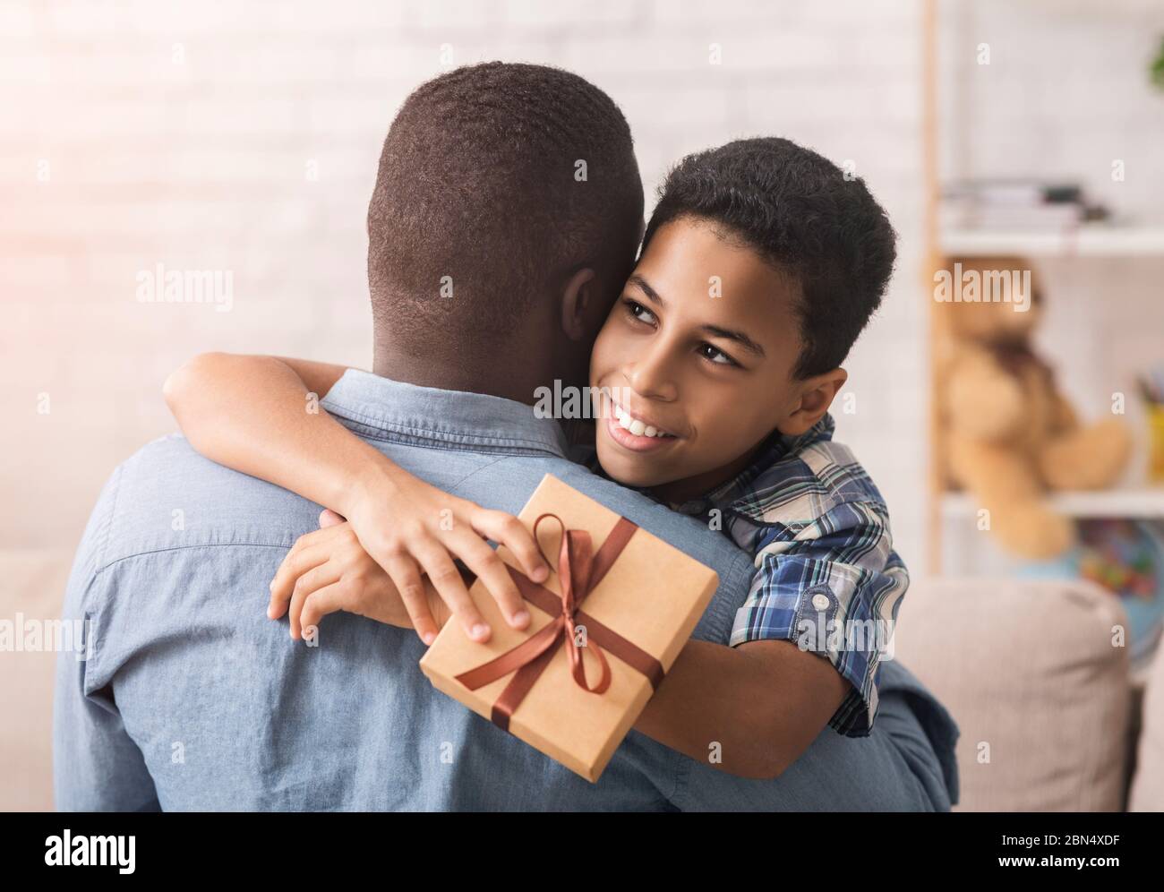 Happy Black Boy Hugging Dad And Giving Him Gift Box Stock Photo - Alamy