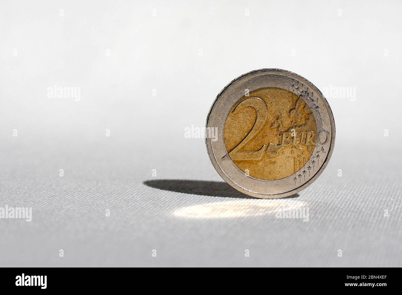 A two euro coin placed in balance on a white background, with copy ...