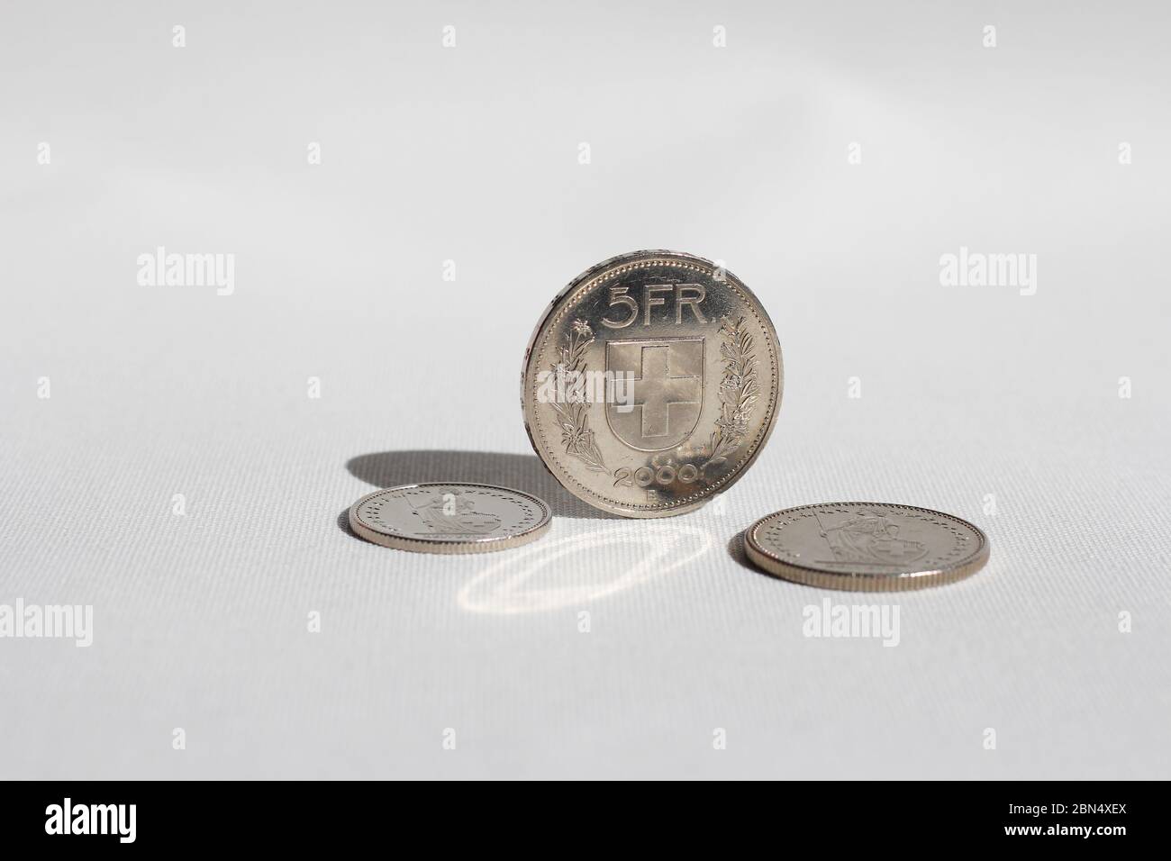 Swiss Franc coins, one, two and five, standing on a white background ...